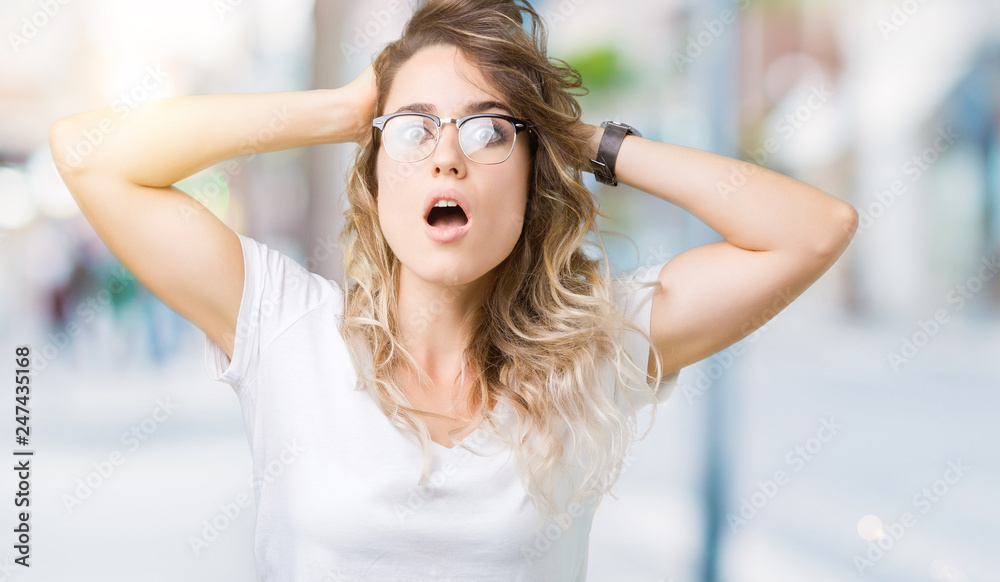 Beautiful young blonde woman wearing glasses over isolated background ...