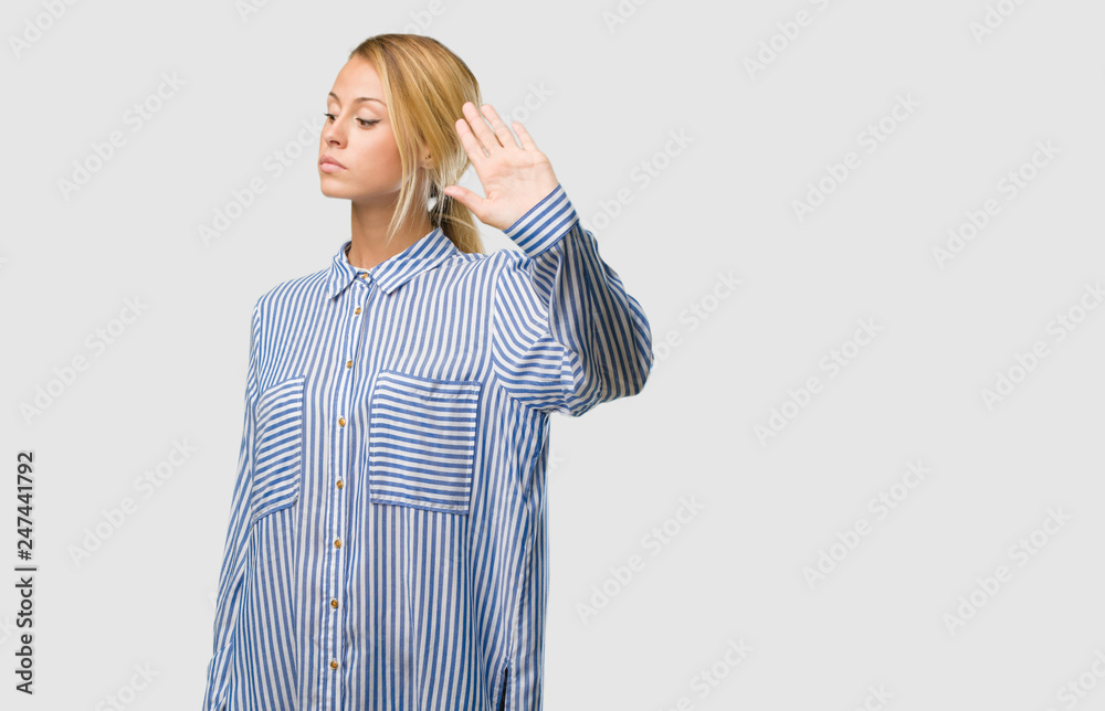 Portrait of a young pretty blonde woman serious and determined, putting ...