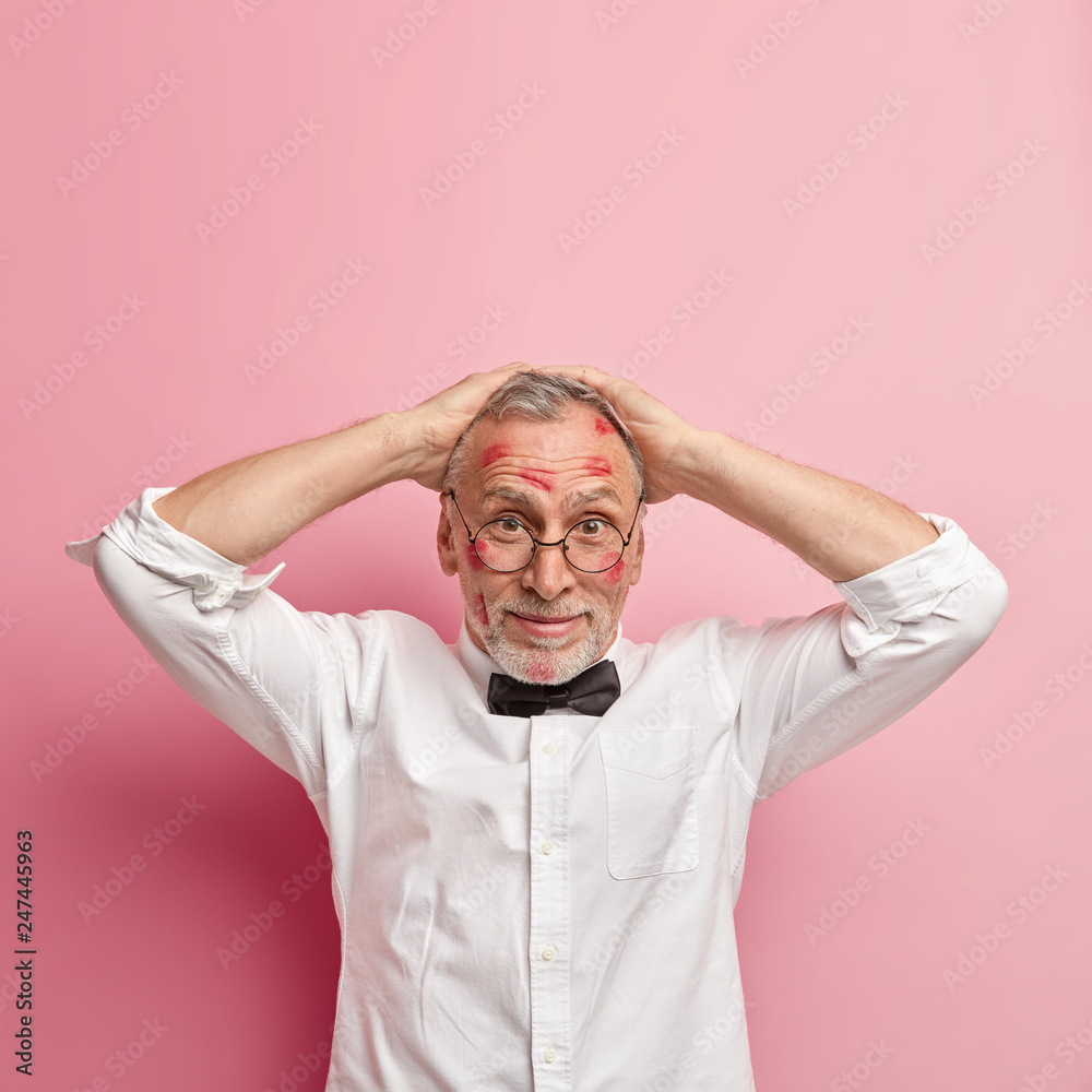 Vertical shot of funny bearded senior male model keeps both hands on ...
