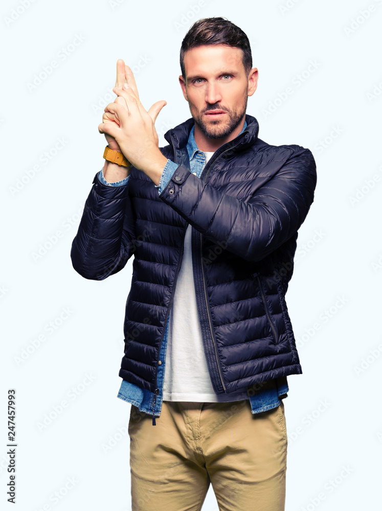 Handsome man wearing winter coat Holding symbolic gun with hand gesture ...