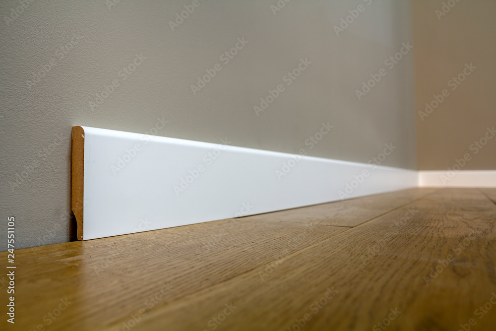 Wooden or plastic white floor plinth installation in big empty room on ...