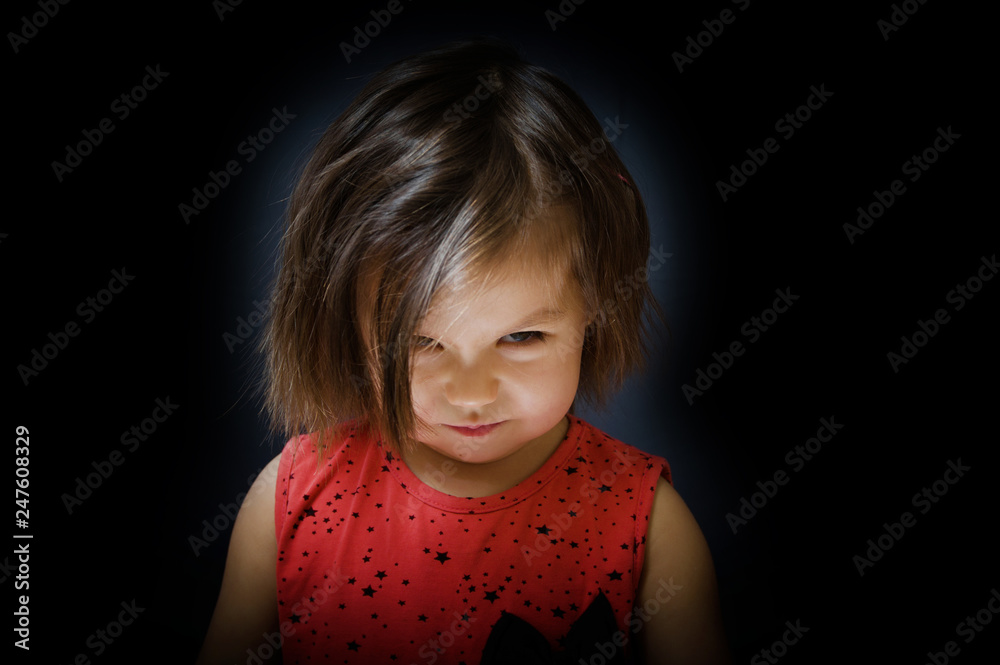 Tricky child look up and smiling sly on dark background. little girl ...