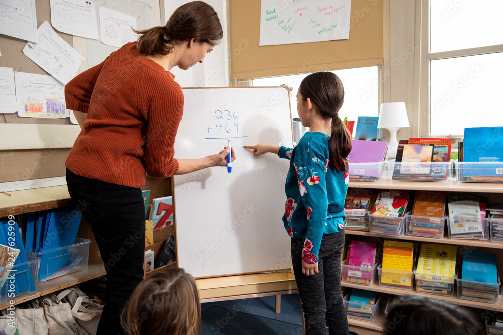 Girl solving math problem with teacher Stock Photo | Adobe Stock