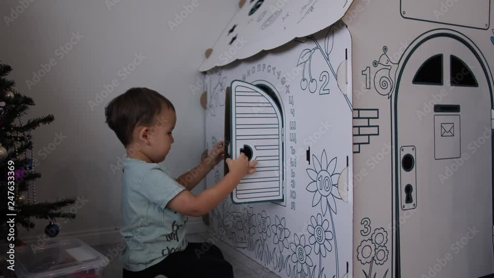 Child and paper house. Baby opens and closes a cardboard window on a ...