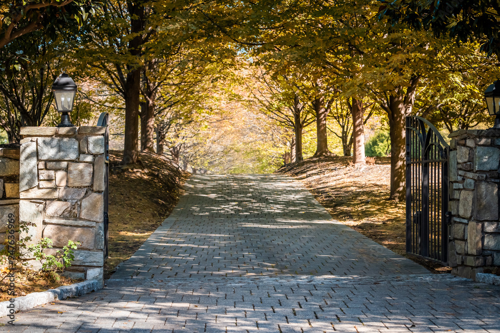 Gated open entrance with road during golden autumn in rural countryside ...