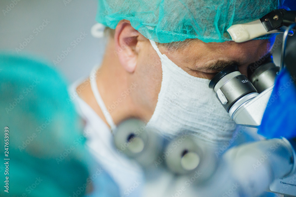 The doctor looks through a microscope. Surgery. Scientist looking ...