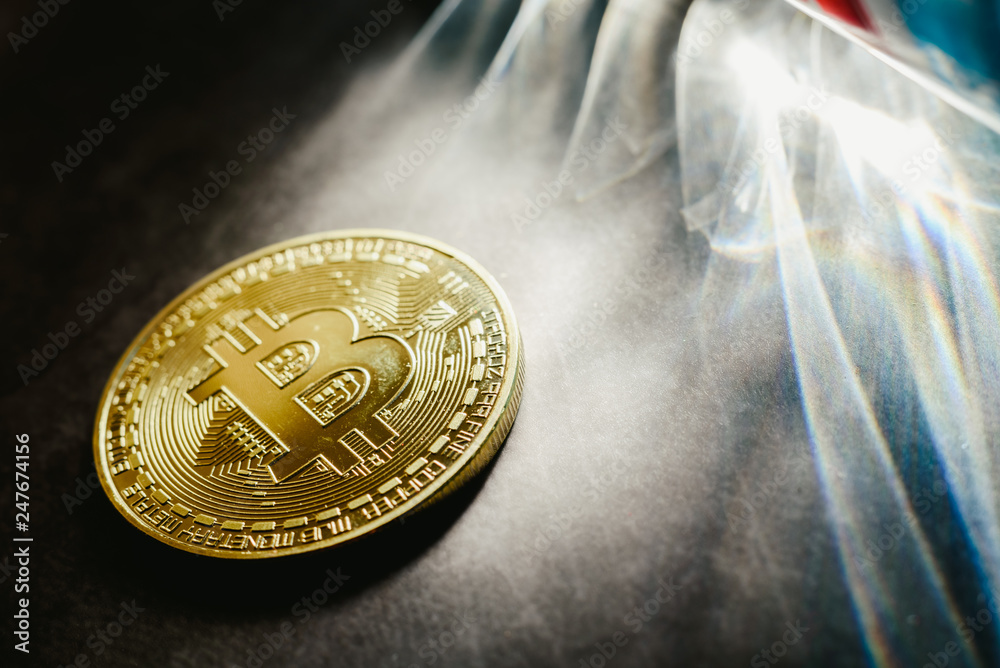 Bitcoin physical coins illuminated by light rays with dark background ...