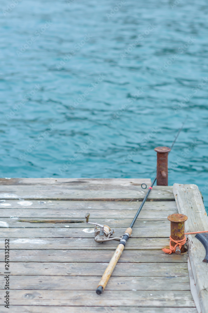 Wooden pier. Fishing rod. Mooring bollards. Fishing in the bay of ...
