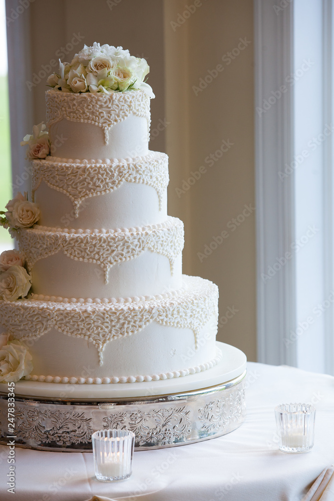 white wedding cake with white flowers and fancy designs on a table ...