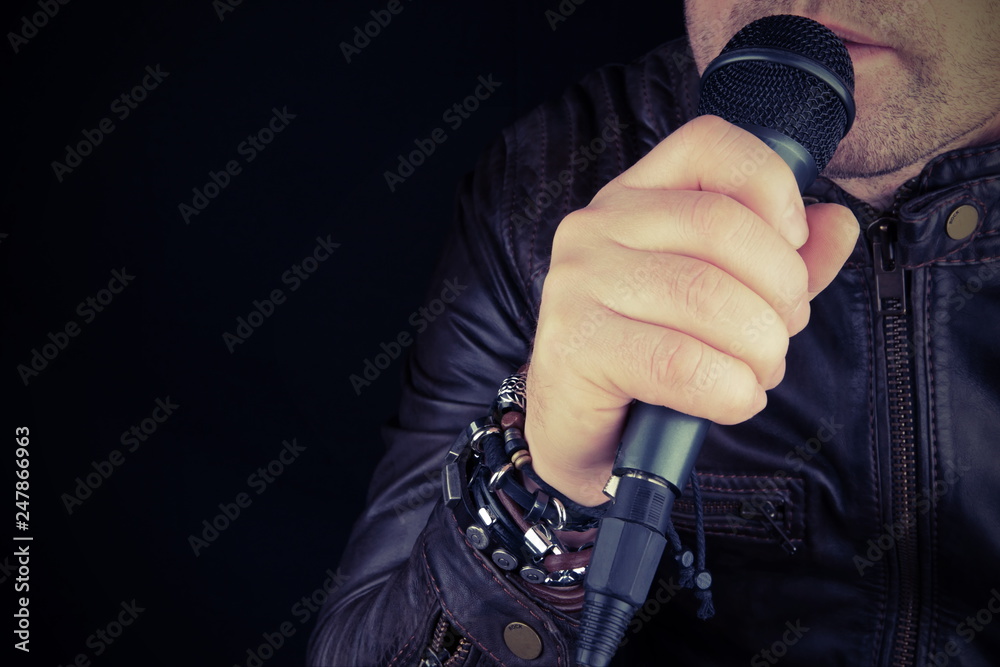 Man hand holding microphone. Leather bracelet and accessory .Hard rock ...