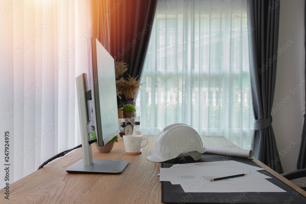 office table with monitor, safety hat, plan design paper and hot drink ...
