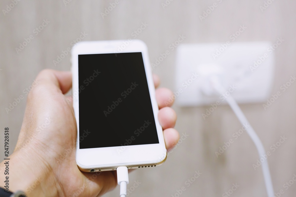 close up hand plugging adapter charge the battery with outlet socket ...