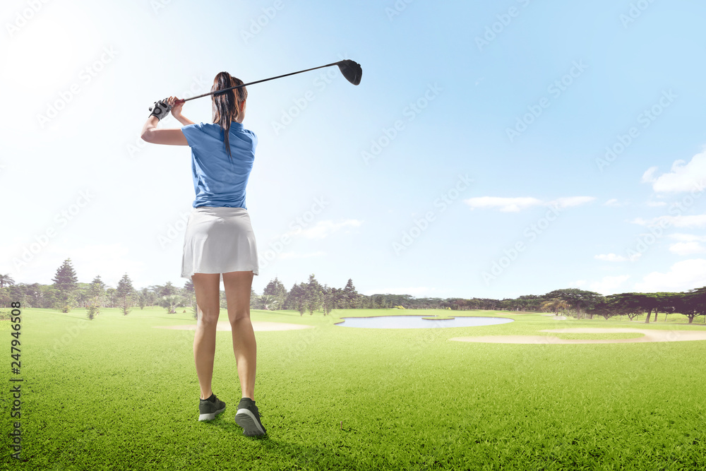 Rear view of asian woman on long drive swing with wood club in the golf ...