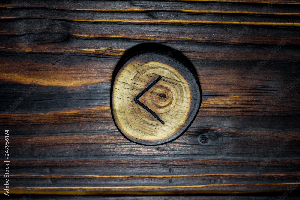 Rune Kaunan (Kaun, Kenaz) carved from wood on a wooden background ...