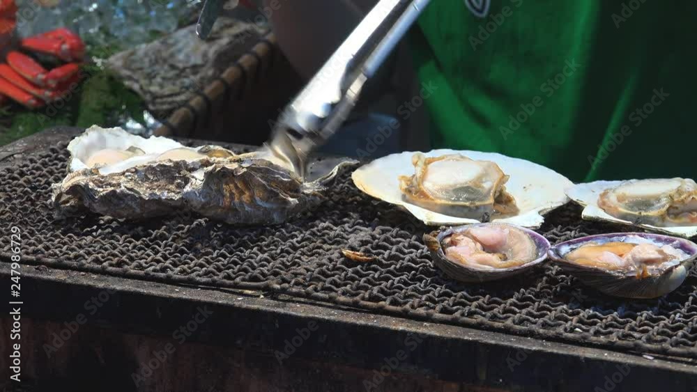 Grilling of big oysters, scallops & shellfish on a street food court ...
