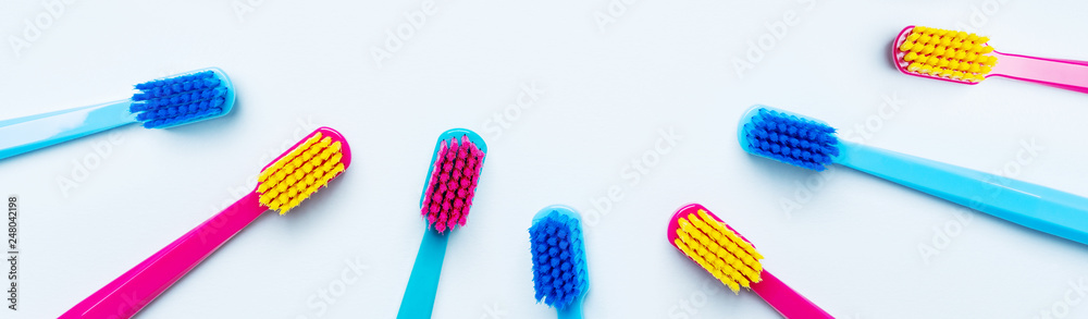 Colorful tooth brushes with bright color bristles on a light pastel ...