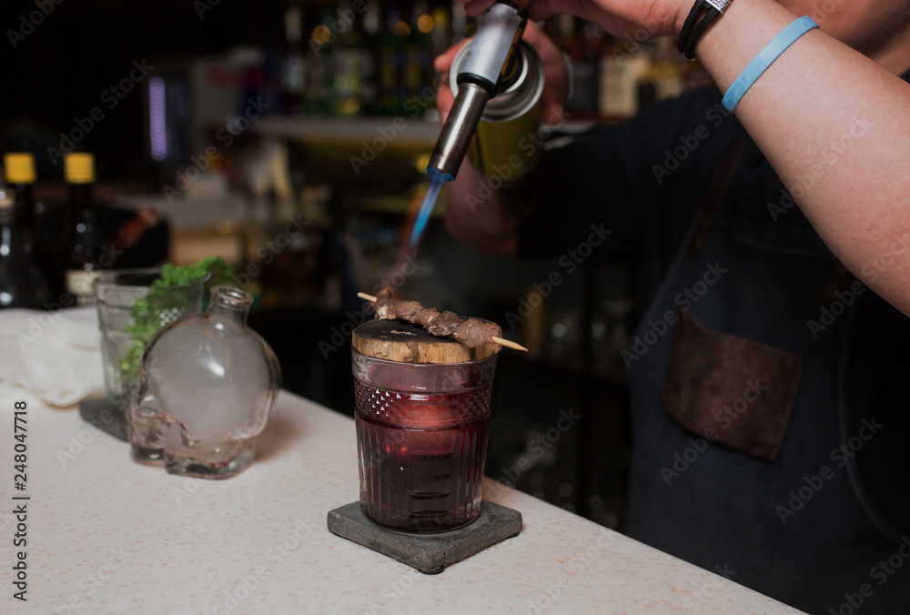 Exotic healthy Cocktail, bartender with blaze blowtorch burning ...