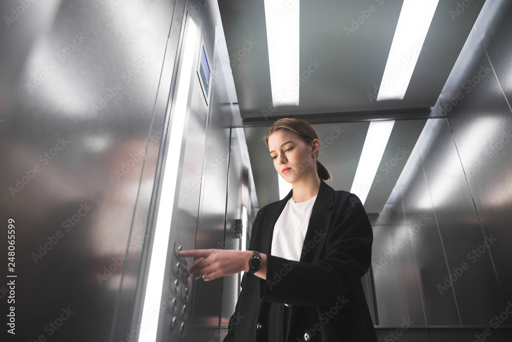 Beautiful young businesswoman wearing black suit is using elevator ...