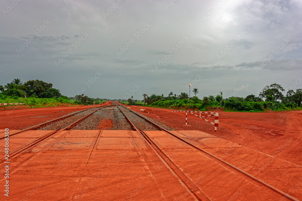 Crossroad of red soils Guinea countryside road and railroad of bauxite ...