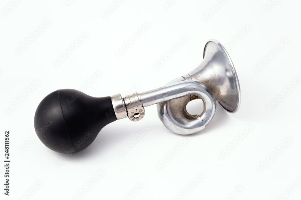 A worn iron horn or klaxon from a vintage car or bicycle lies ...