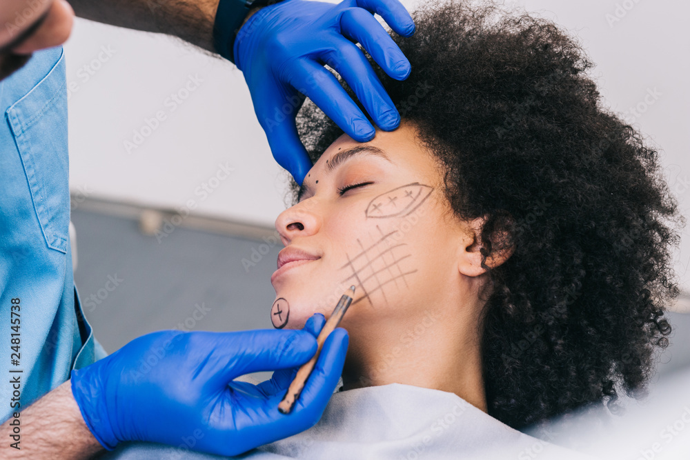 Close-up of doctor's hand drawing correction lines on young woman's ...
