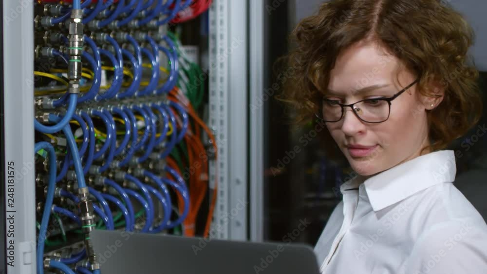 Close up view of young female IT engineer in glasses standing beside ...