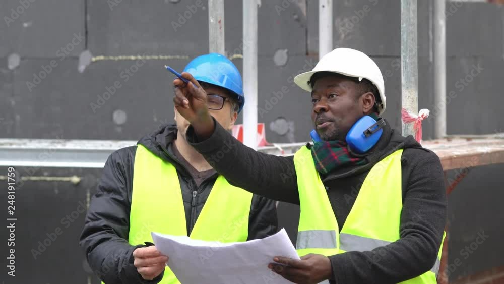 African American and Caucasian male engineers wearing safety jacket and ...