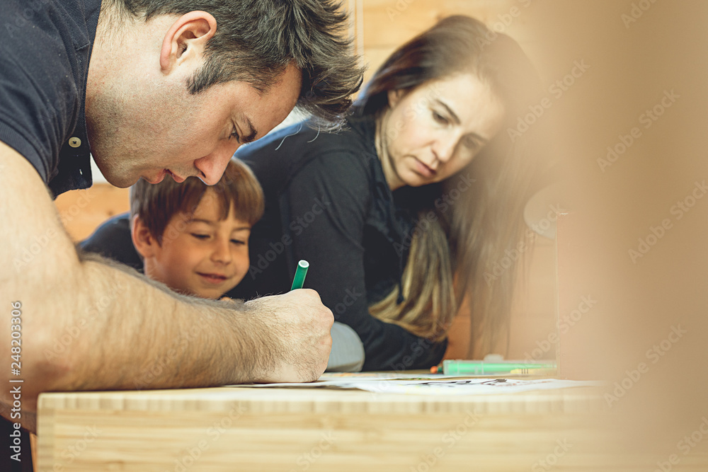 Child painting a picture at home with his parents. Couple assisting ...