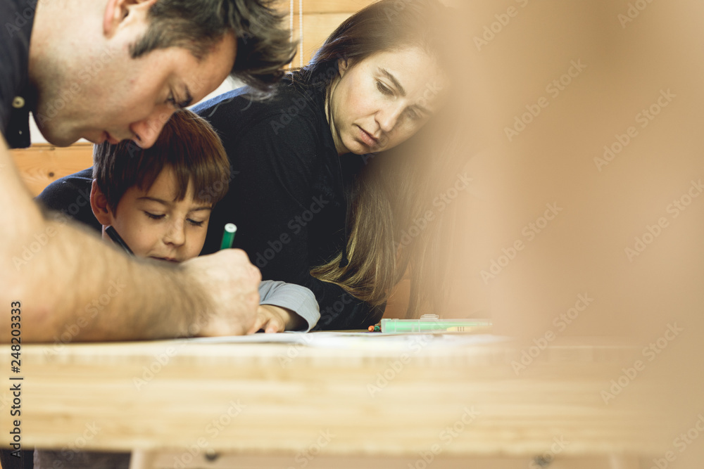 Child painting a picture at home with his parents. Couple assisting ...