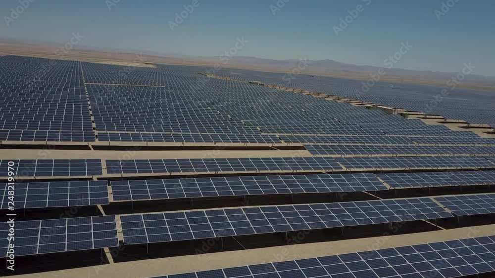Aerial footage of hundreds solar energy modules or panels rows along the dry lands at Atacama ...