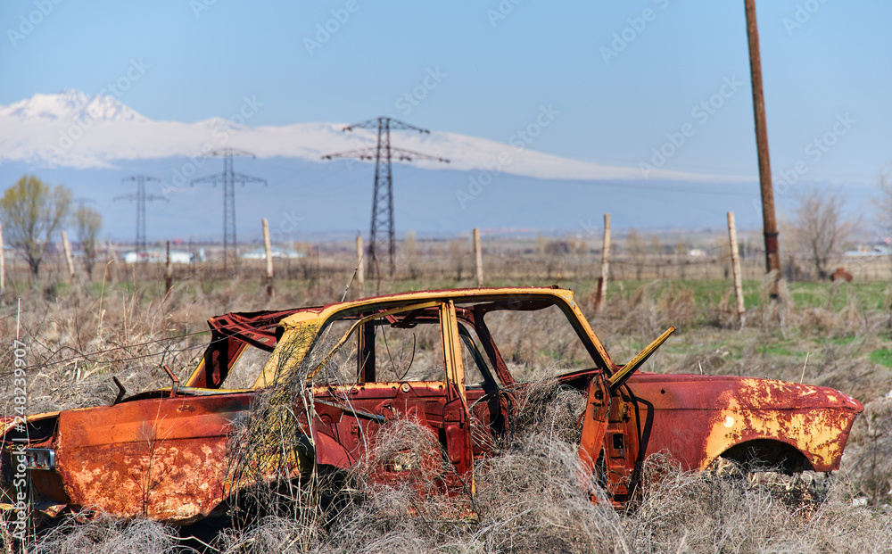 Abandoned and rusty wreckage of an yellow vintage Soviet Russian car in ...