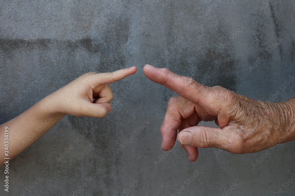The hand of a little fragile girl barely touches the hand of an old ...
