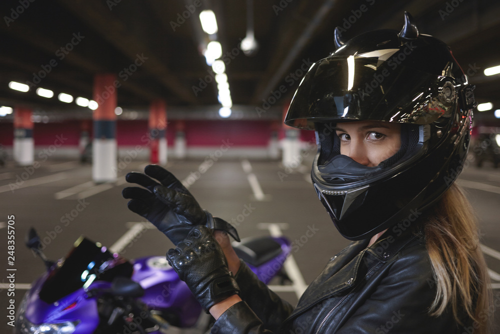 Profile shot of attractive confident young female biker wearing safety ...