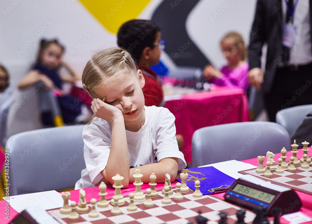Small cute girl infront of chess board on chess tournament look very ...