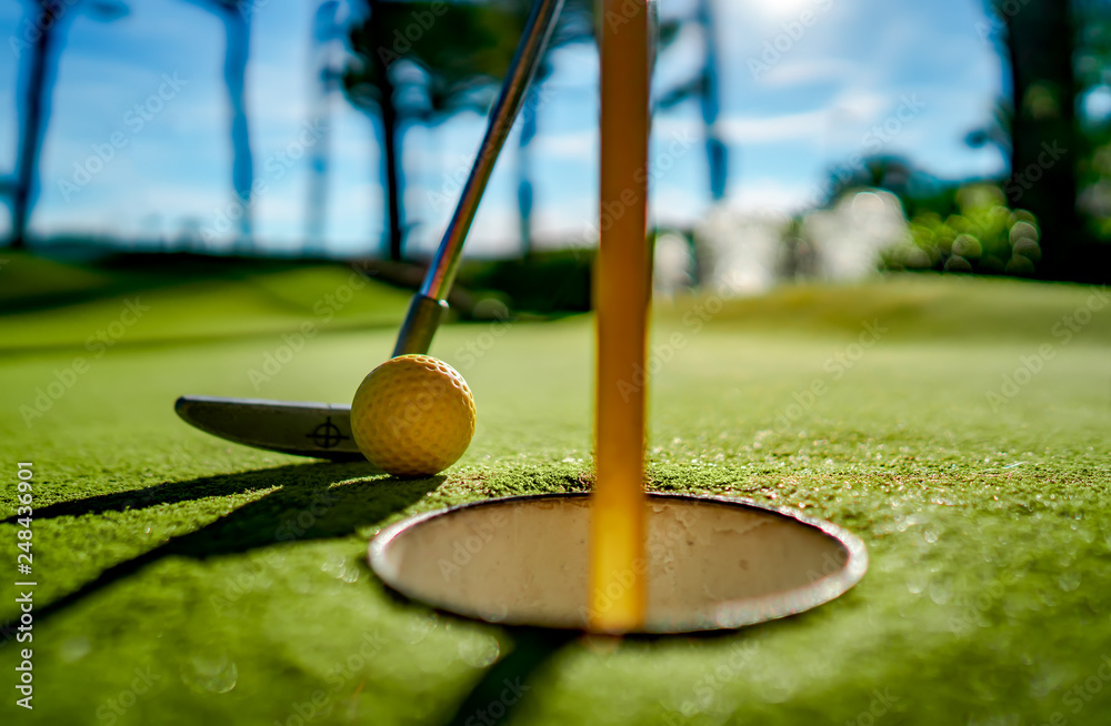 Mini Golf yellow ball with a bat near the hole at sunset Stock Photo ...