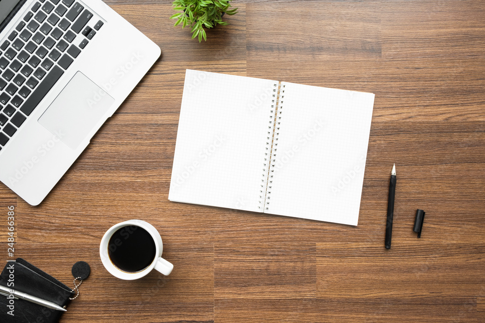 Blank notebook with pen are on top of wood office desk table. Top view ...