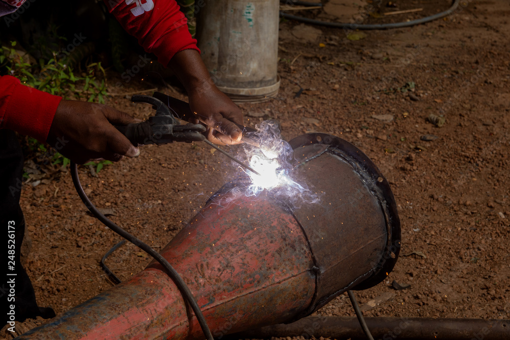 Welder is welding metal piping in construction site Stock Photo | Adobe ...