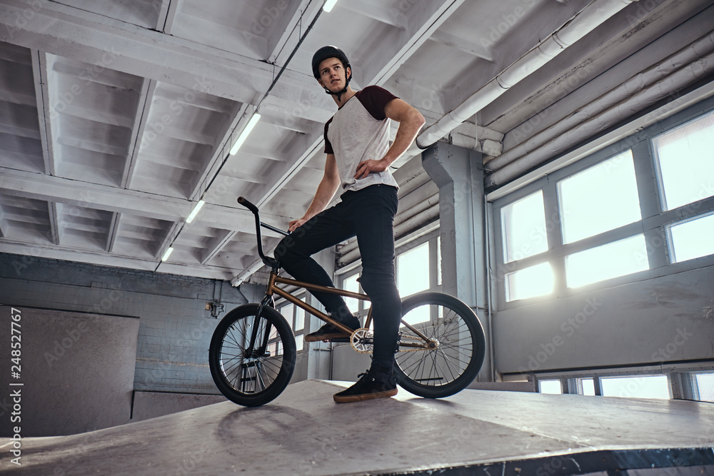 Teenage BMX rider standing with his bike getting ready to jump in a ...