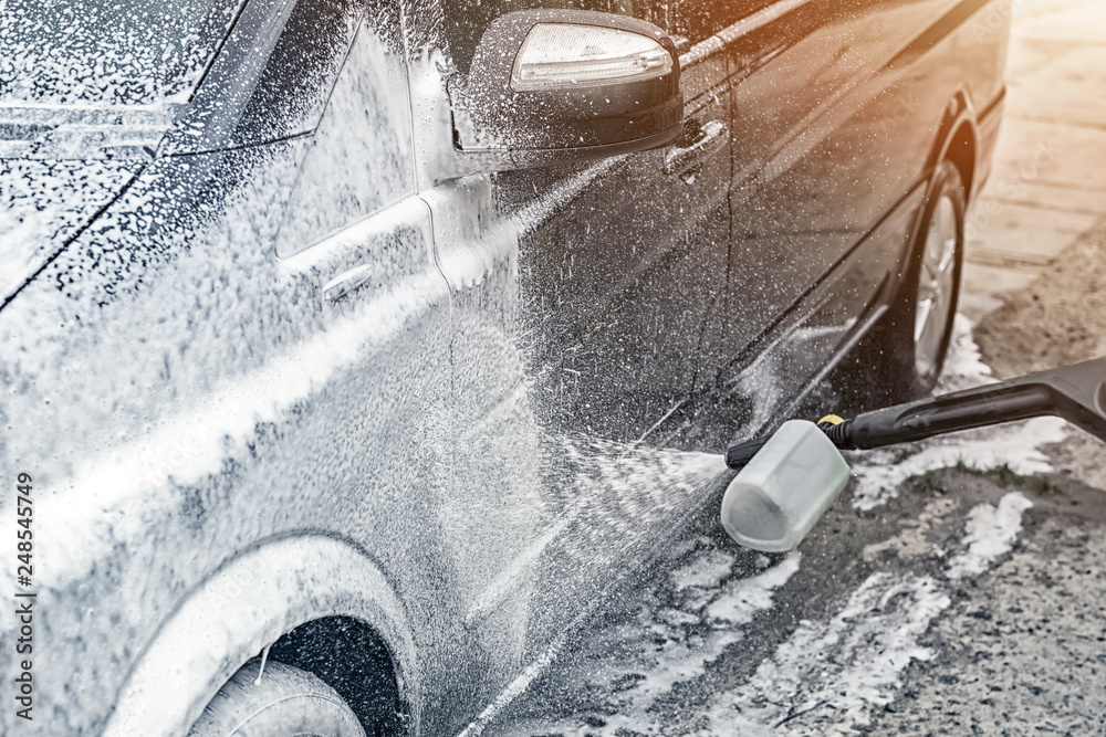 Manual car wash. Washing luxury vehicle with high pressure water pump ...