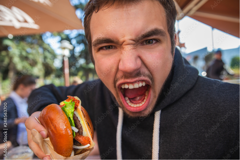Angry young man looking at the camera with his mouth wide open. He is ...