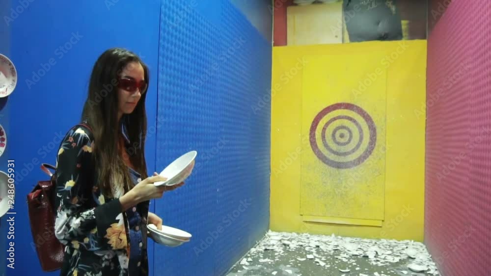 Beautiful girl in slow motion looks at a ceramic plate and throws her ...