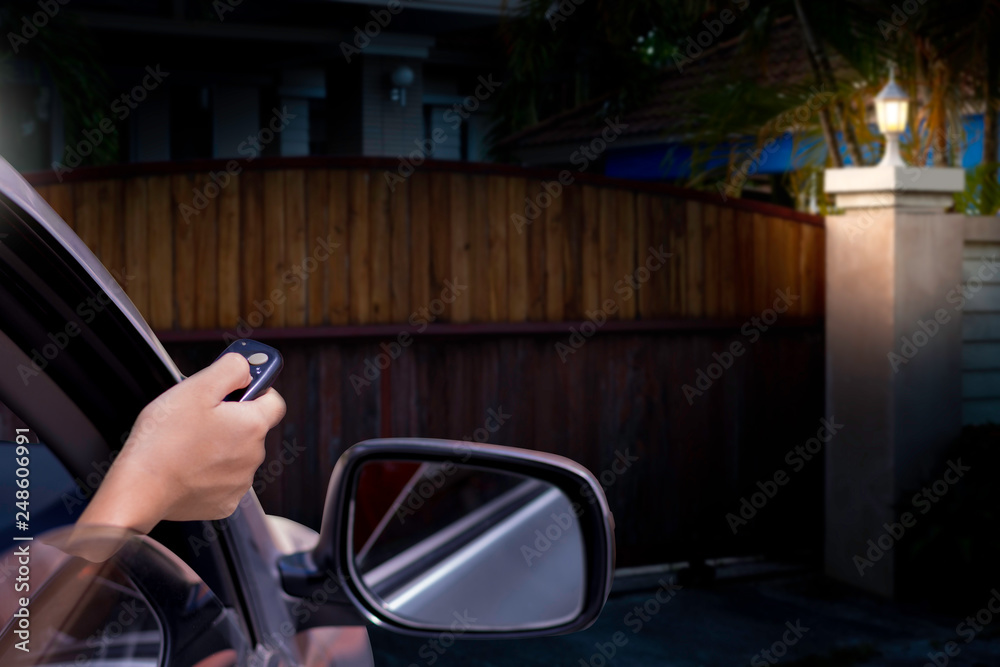 Woman in car, hand using remote control to open the automatic gate in ...