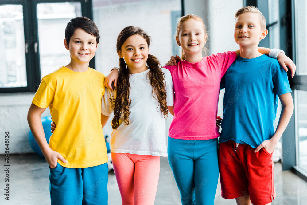 Joyful preteen children smiling and embracing in gym Stock Photo ...