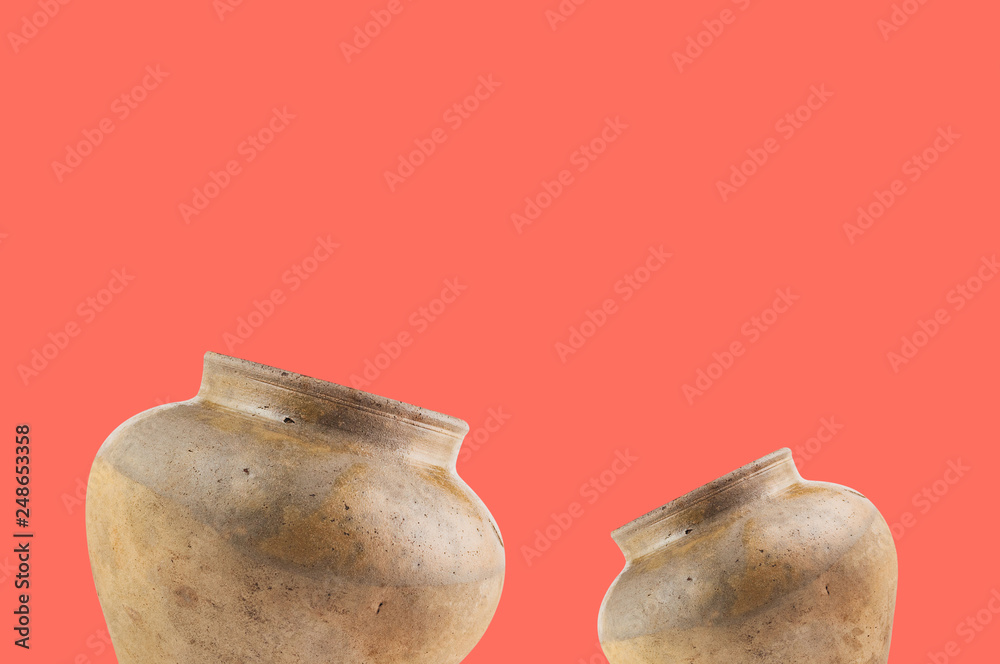 Pair of old antique worn and dirty vases on coral color table with copy ...
