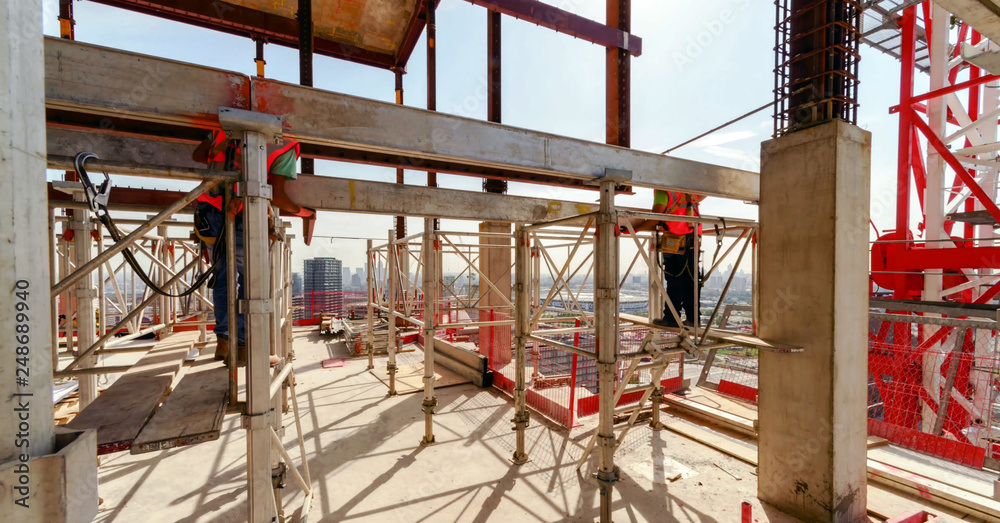 high building under construction with workers in the construction site ...