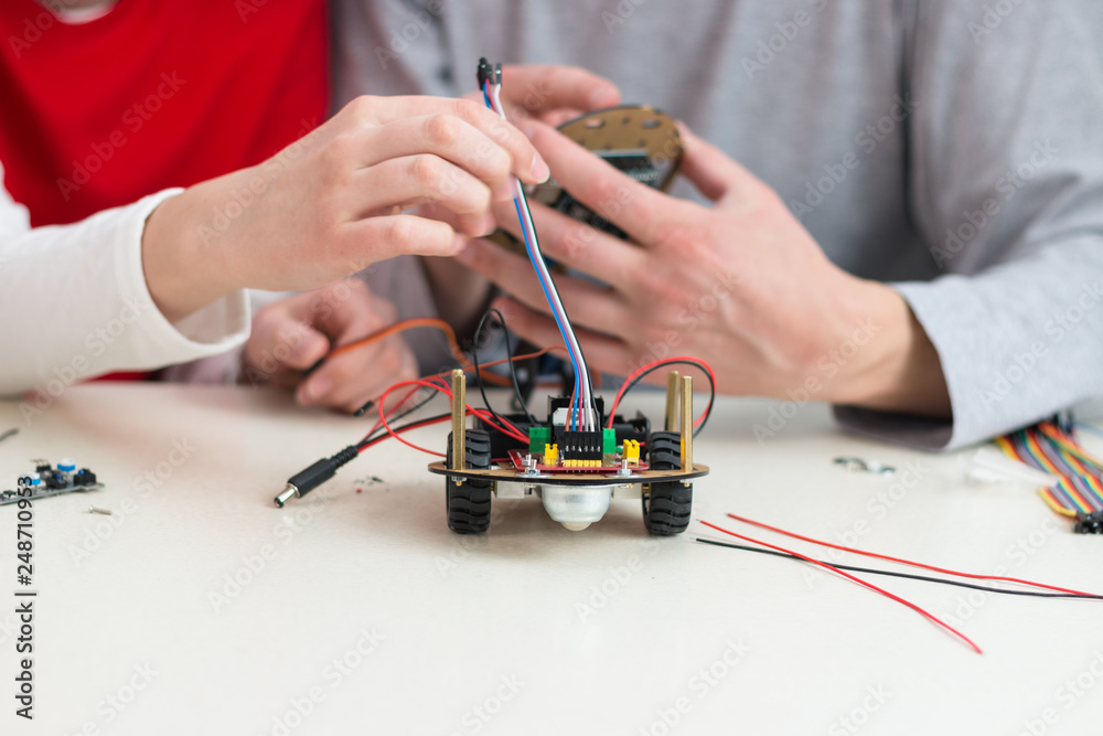 A teenager boy with his dad teacher collects a handmade robot working ...