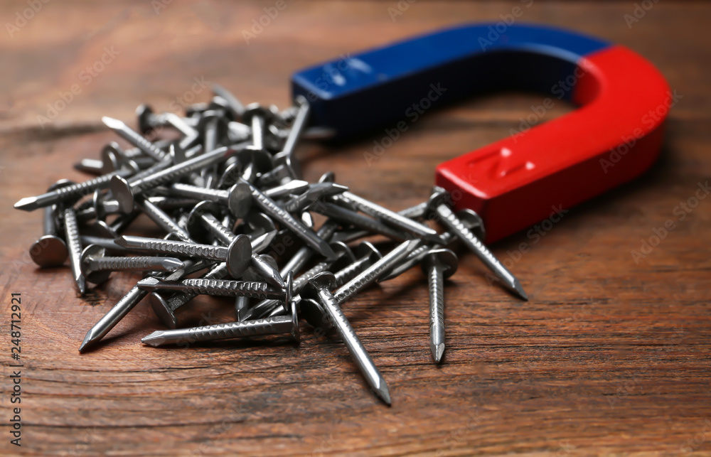 Magnet attracting nails on wooden background, closeup Stock Photo ...