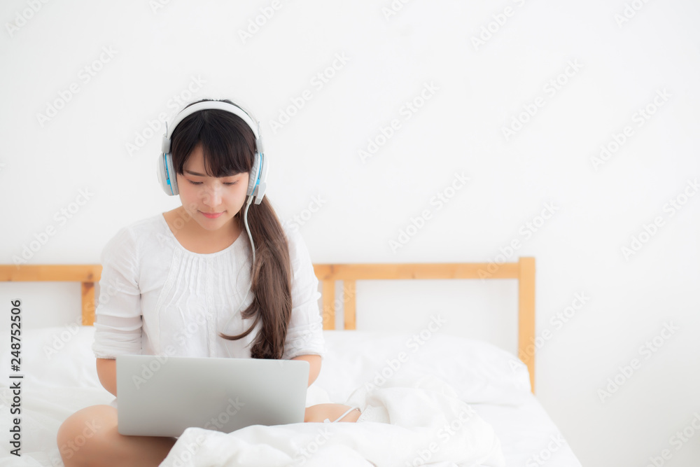 Beautiful young asia woman lying in bedroom using laptop computer ...