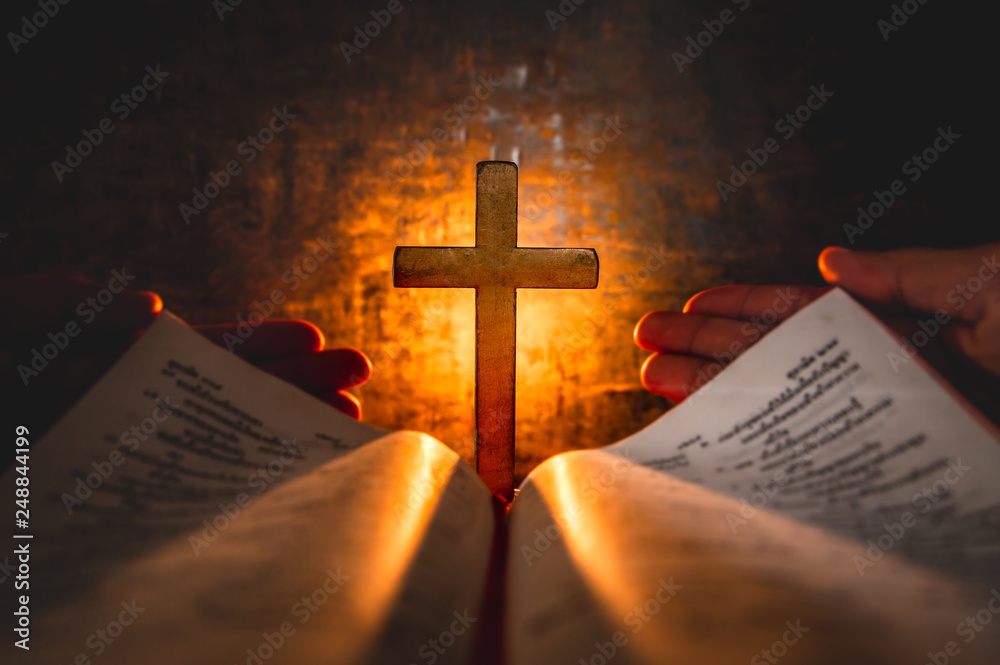 opening bible with cross in middle at light of candle background on ...