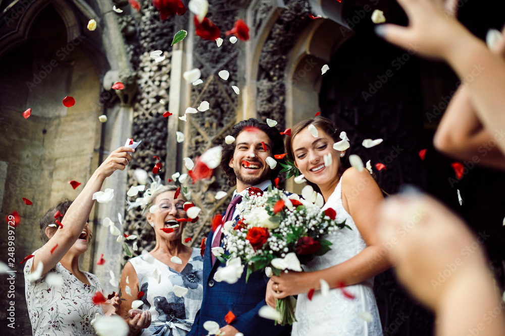 Foto de Family throwing rose petals at the newly wed bride and groom do ...